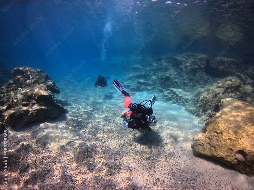 Two scuba divers exploring underwater seascape with rock formations ...