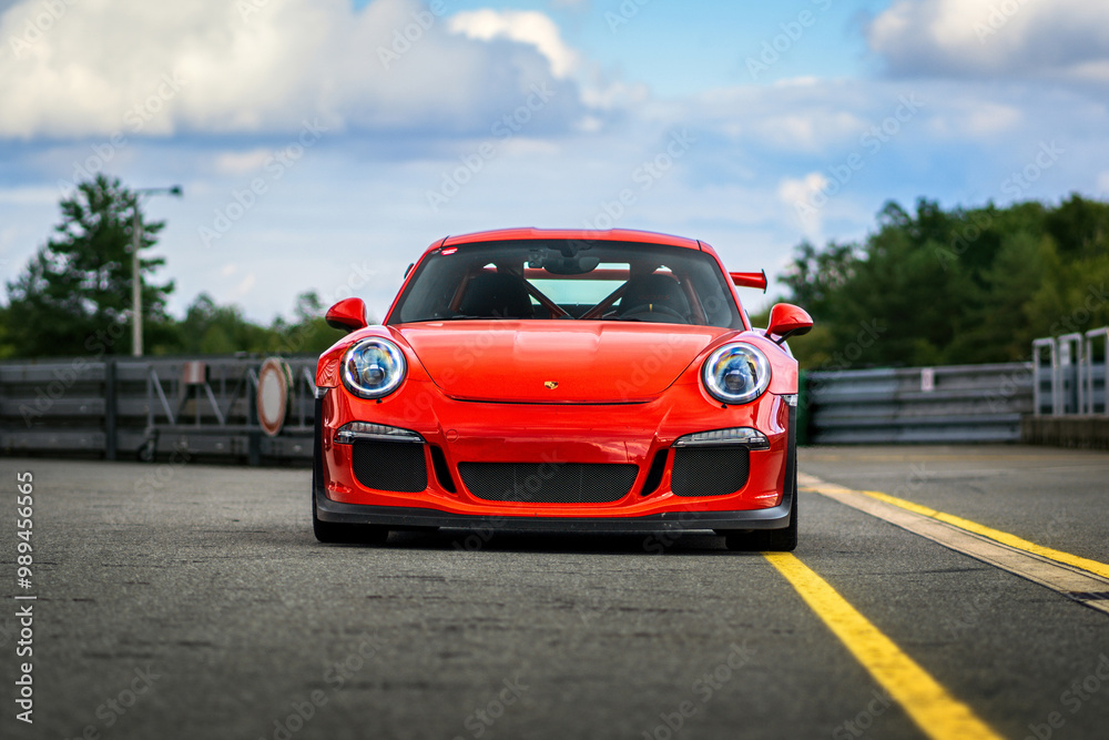 Red Porsche 911 sports car parked outside on an asphalt road. Front ...
