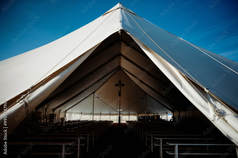 Large outdoor church tent with neatly arranged wooden benches and a ...