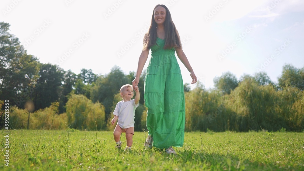 Mom and baby taking the first steps. Walk kid boy concept. Mom holds ...