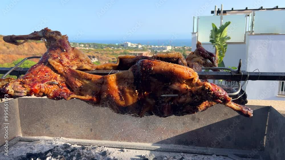 Roasting whole lamb on a spit metal rotating stick over fire, golden ...
