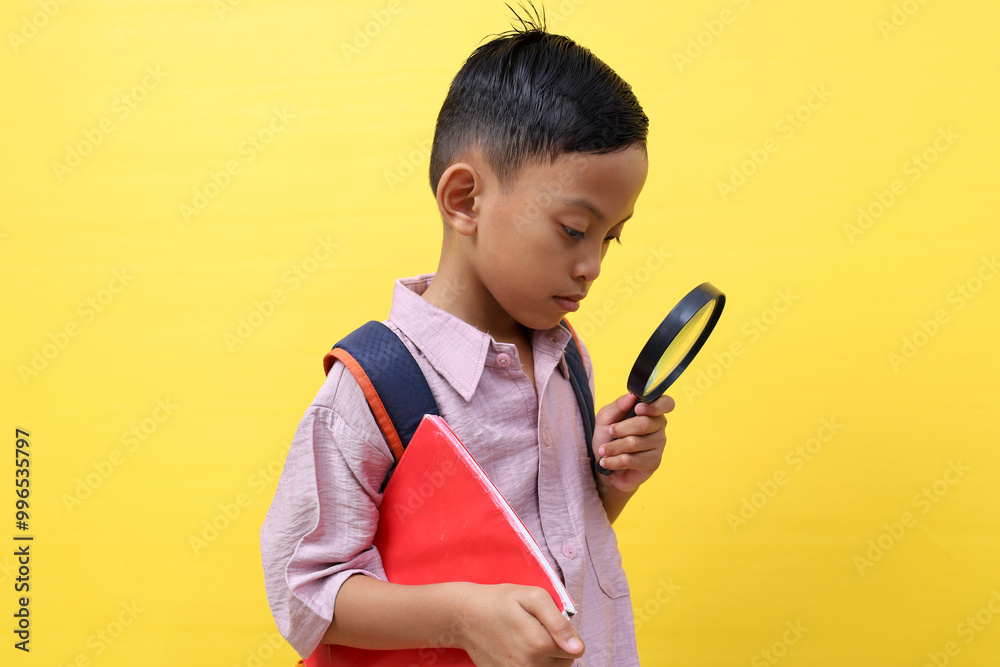Smart asian schoolboy detective looking through magnifying glass with ...