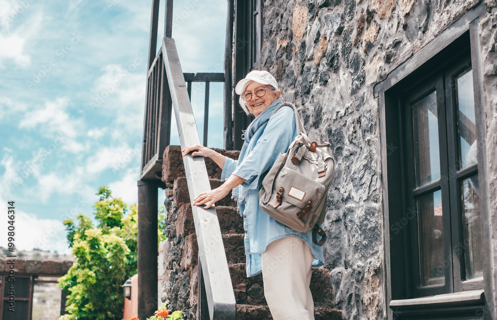 Smiling traveler senior woman in outdoor excursion in rustic mountain ...