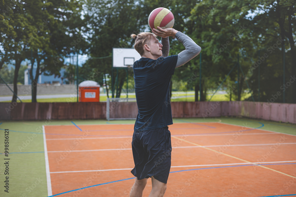 Basketball player prepares to shoot the ball on an outdoor court ...