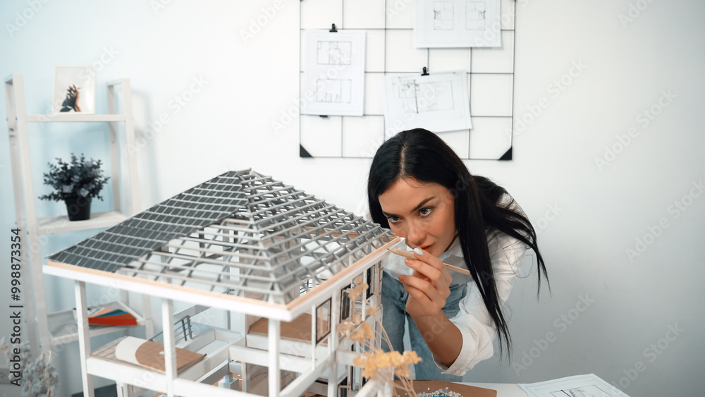 Young beautiful caucasian architect engineer turns house model around ...