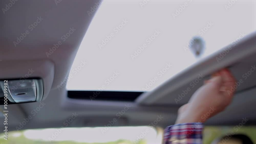 Hand adjusting the car's sunroof switch, focusing on the movement and ...