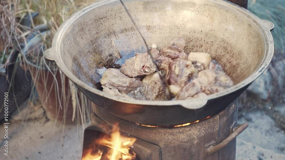 Chef mixes fried meat in large cauldron with slotted spoon. Roast beef ...