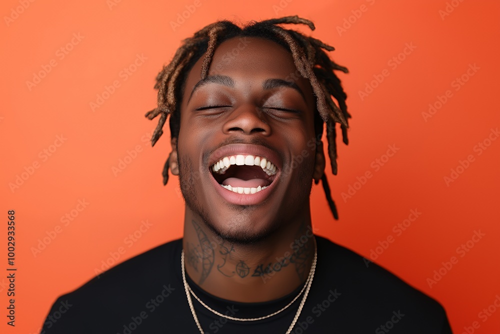 Portrait of a young black man with dreadlocks, laughing with his eyes ...