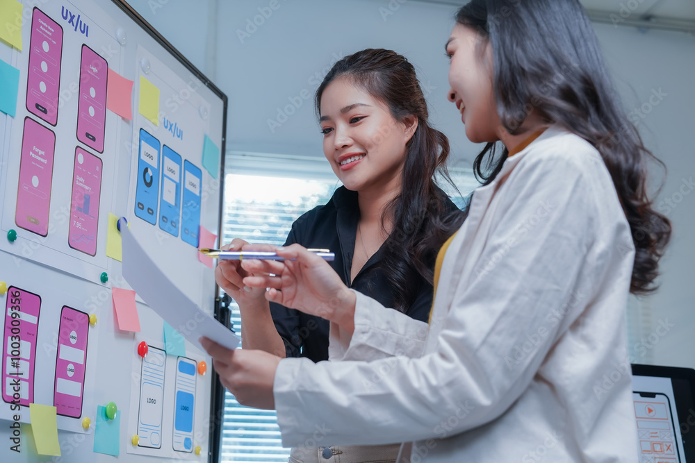 Two asian ui/ux designers are discussing the mobile app interface ...