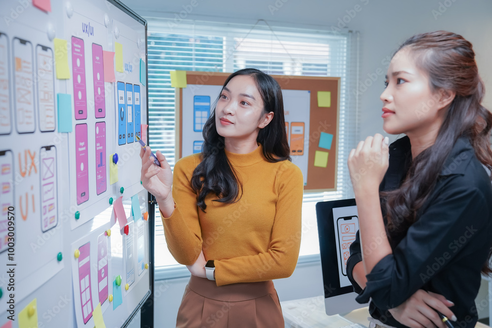 Two Asian Female Ui Ux Designers Are Discussing Over Mobile App Interface Wireframe Design