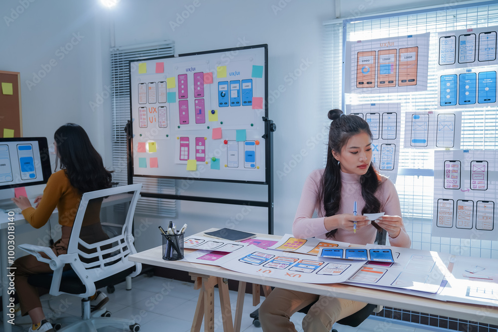 Two female ui/ux designers are working on a mobile application ...