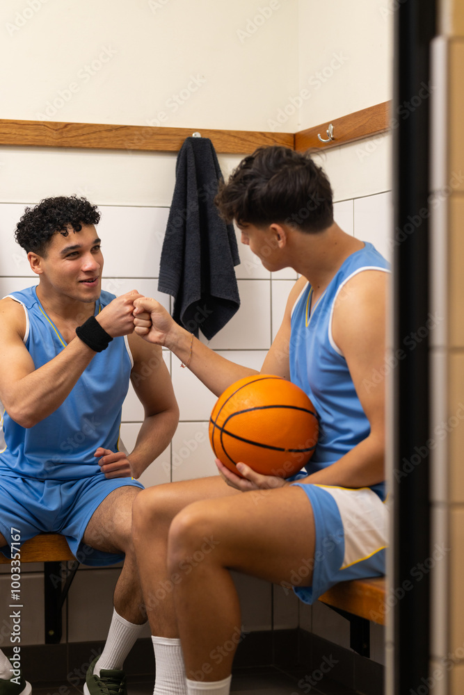 Diverse Basketball players in locker room, fist bumping and holding ...