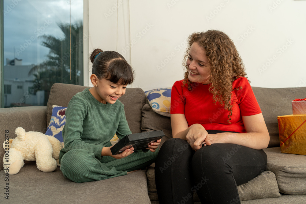 Mother showing an old VHS video cassette to her confused little girl ...