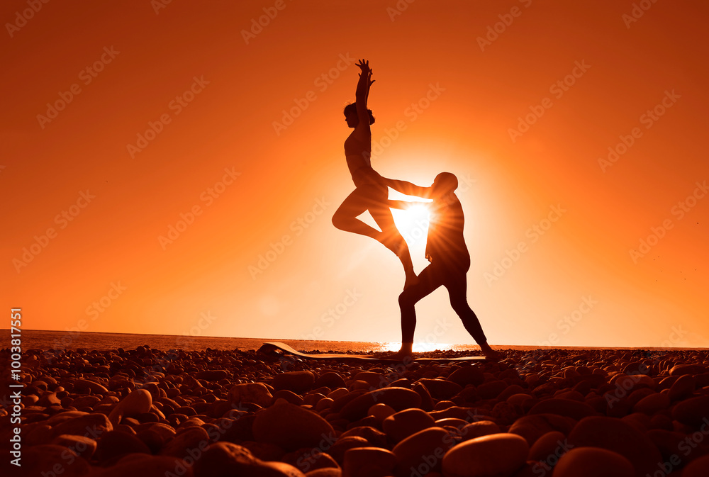 Silhouette of fit sporty couple practicing acrobatic yoga with partner ...