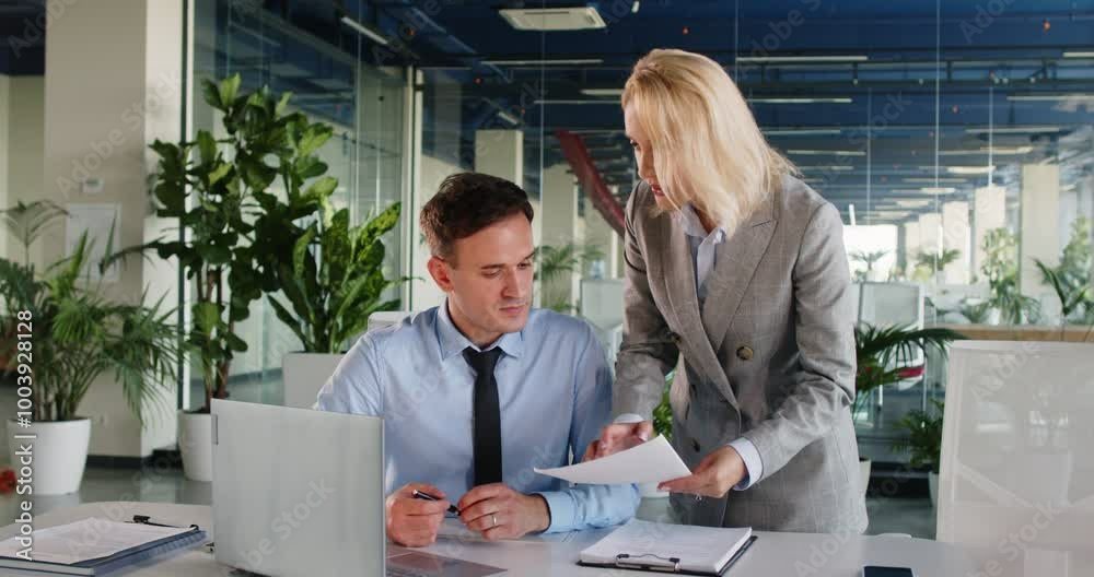 Two colleagues in office work together on task using paper documents ...