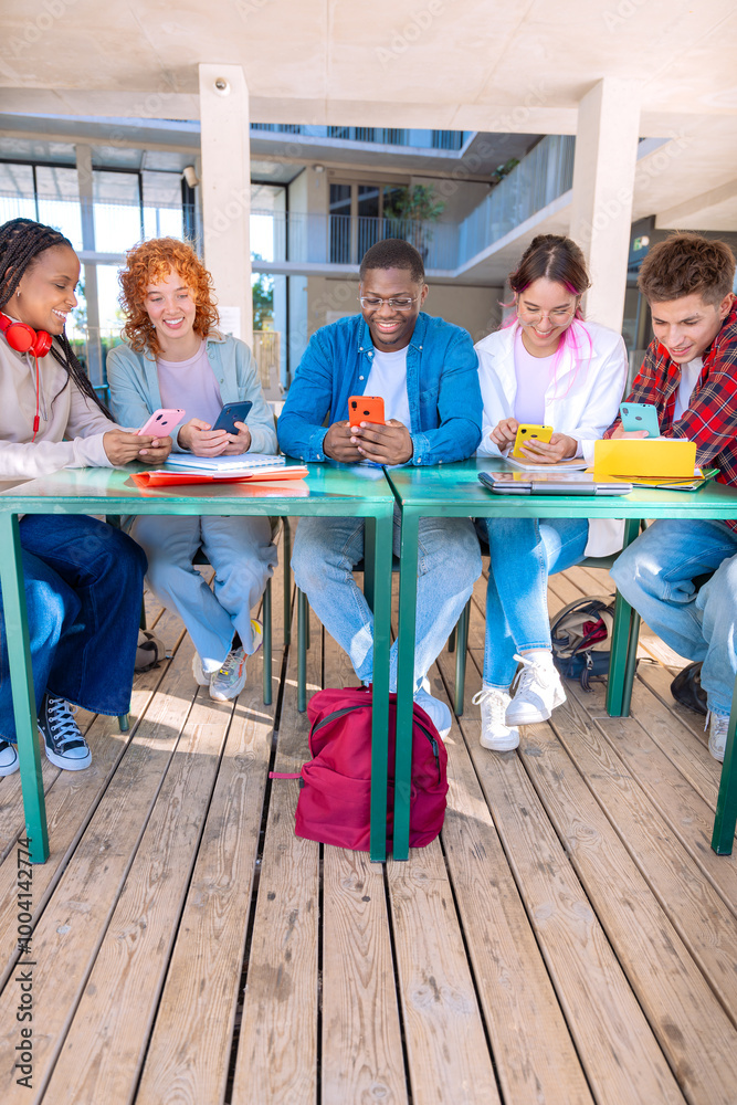 group of five happy students are studying outdoors at university, using ...