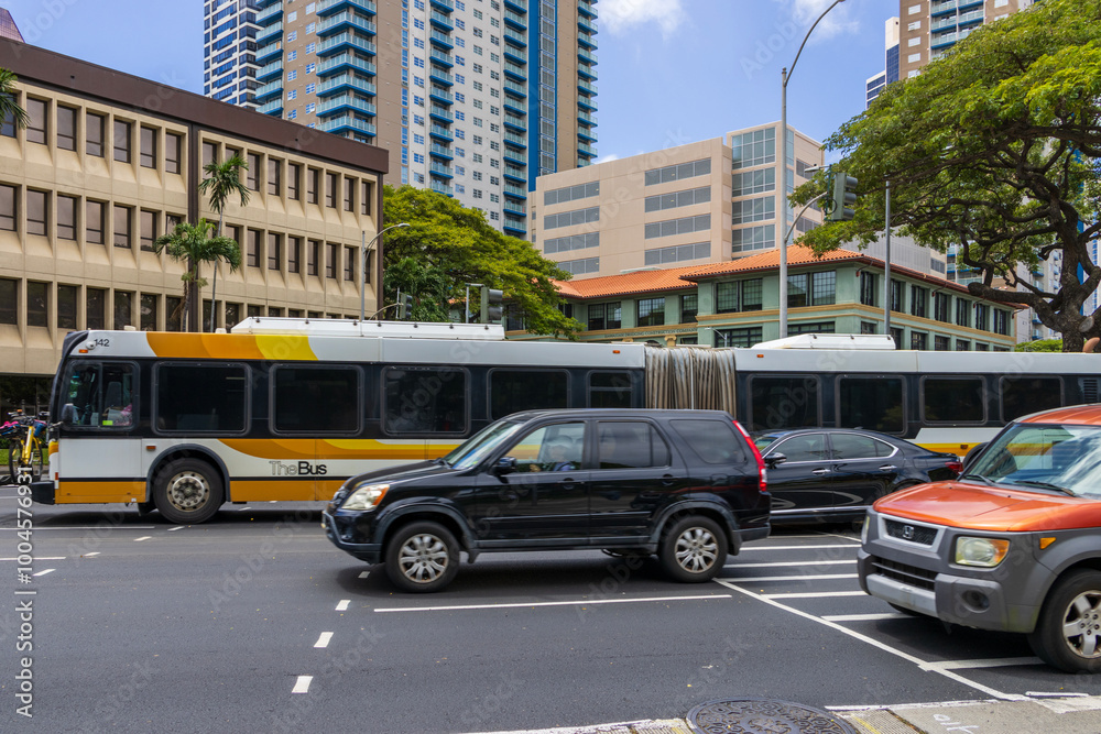 cars, trucks and buses driving on a street with skyscrapers, hotels and ...