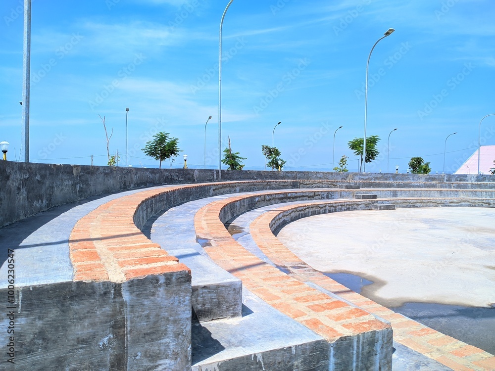 Amphitheater with red brick steps under a clear blue sky. Streetlights ...