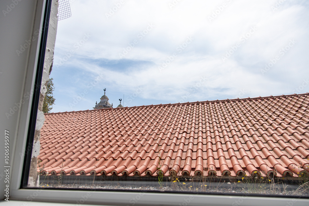 View through a window of a traditional red clay tile roof under a ...