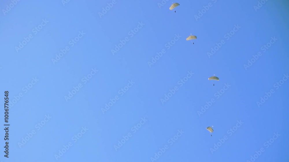 military paratroopers descends in vertical, single-file formation under ...