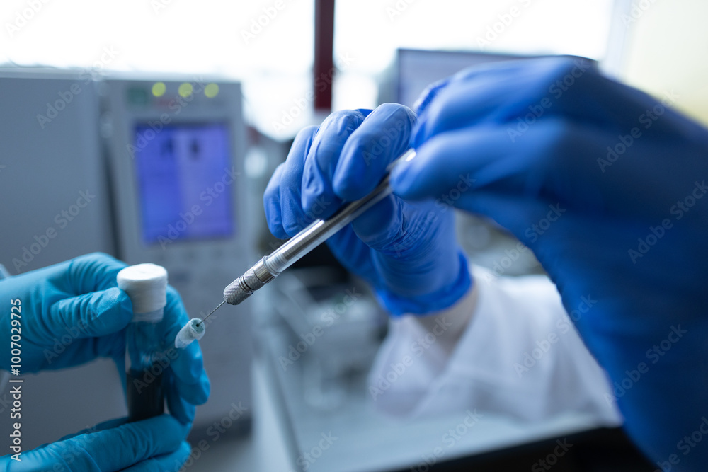 Scientist injecting a sample via the autosampler of HPLC system. High ...
