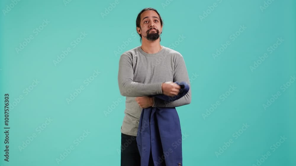 Man holding jacket in one hand while looking around, contemplating ...