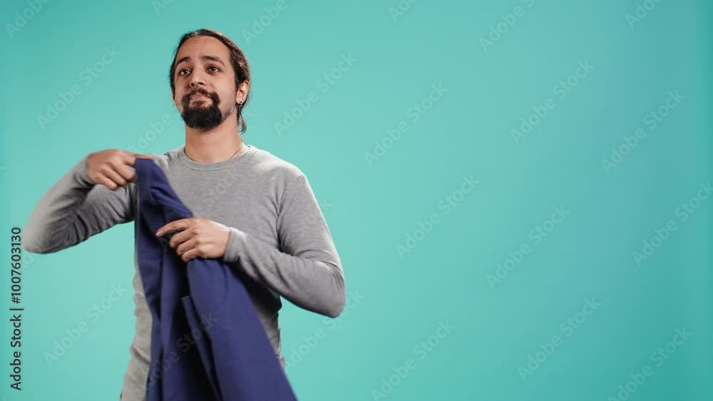 Man holding jacket in one hand while looking around, contemplating ...