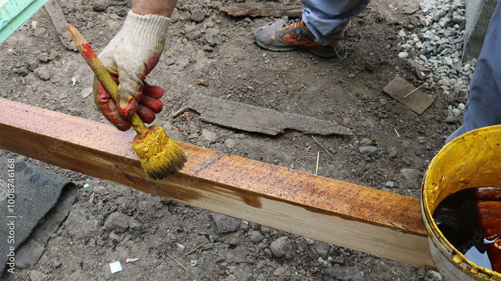 At a construction site a man in work clothes and gloves holds a brush ...