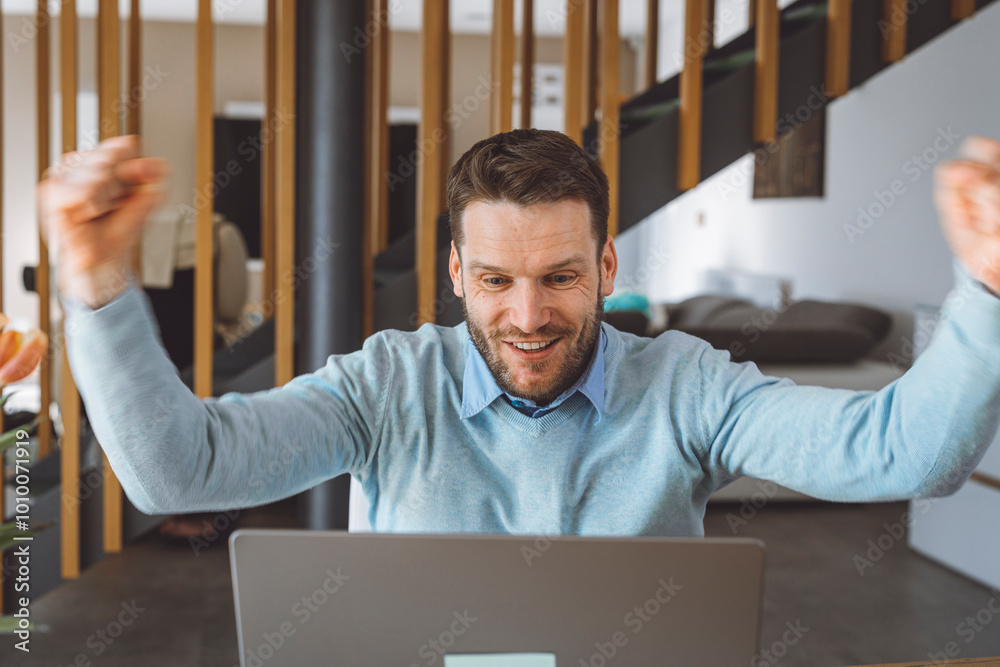 Excited man full of energy sitting behind laptop with big smile on his ...