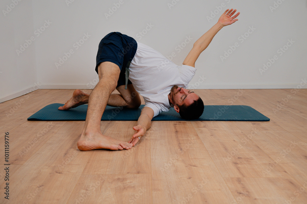 Latin man in a variant of the cat pose, with the body bent downward and ...