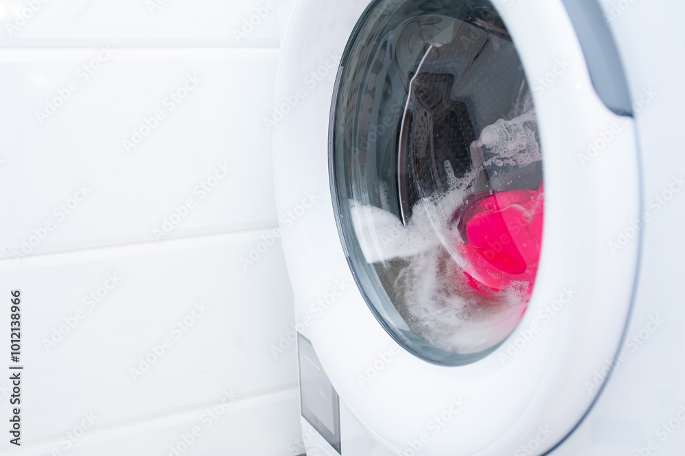 Washing machine with colored clothes and foam inside. Front view ...