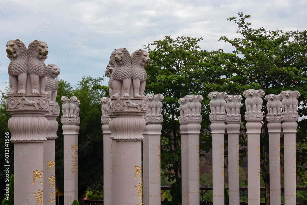 Row of tall, cylindrical columns with intricate carvings and lion stone ...