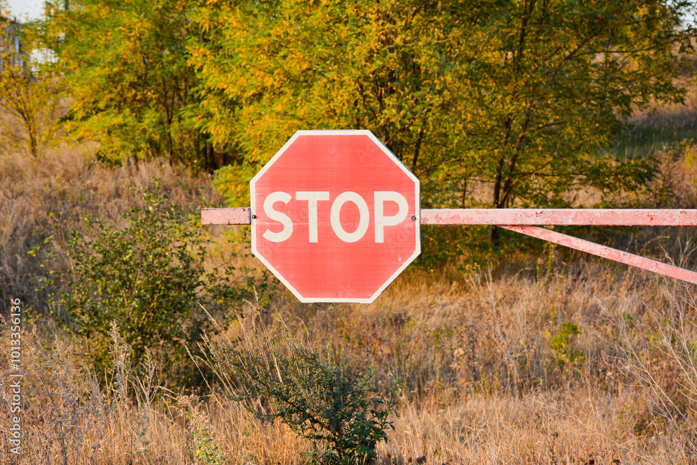 Old road sign stop on the barrier. Rumpled road sign on a greenery ...