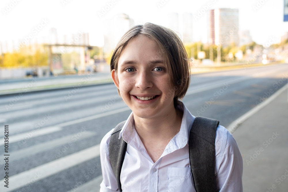 Portrait of smiling 12 year old boy in white shirt with backpack on his ...