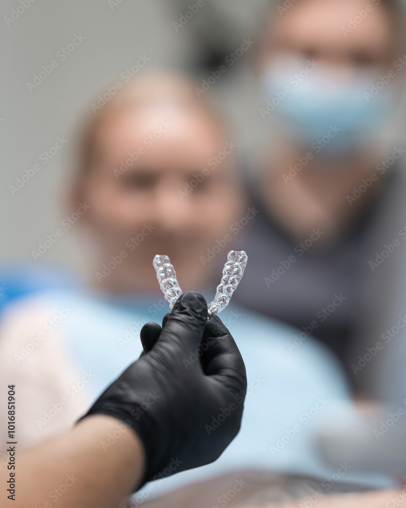 Dental aligners in dentist's hand. Demonstration to patient of ...