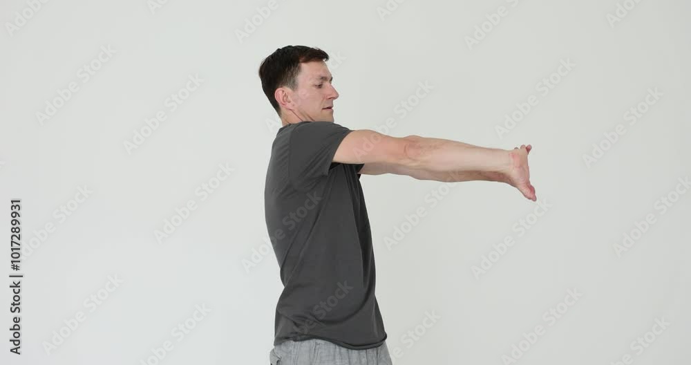 Concentrated man performs arm stretches on white background. Sportsman ...