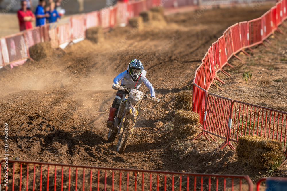 Motocross rider taking a turn on a muddy track during an outdoor ...