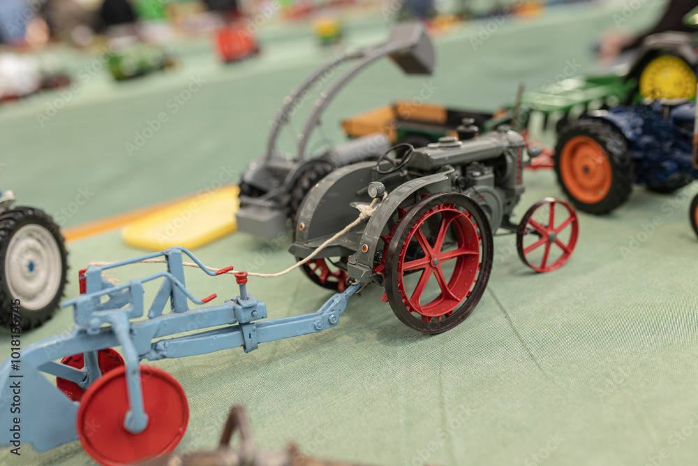 Miniature model farm tractor pulling a blue plow at an agricultural ...