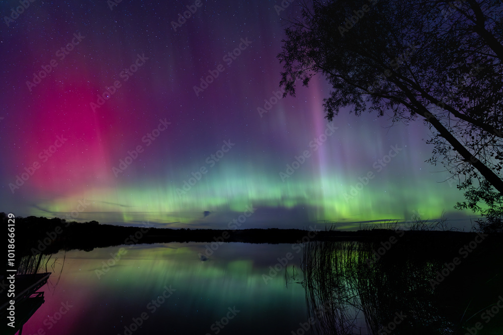 Northern Lights erupt over a Minnesota lake in the dark sky overhead ...