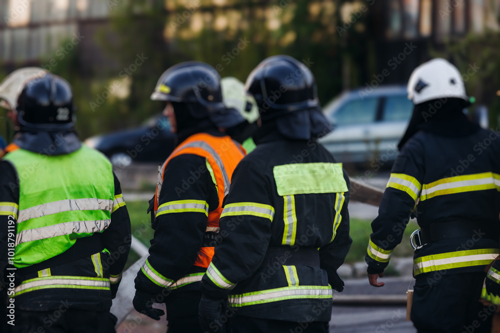 Group of fire men in uniform during fire fighting operation in the city ...