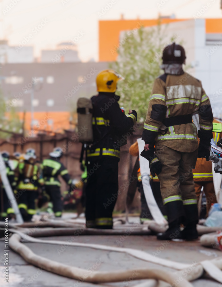 Group of fire men in uniform during fire fighting operation in the city ...