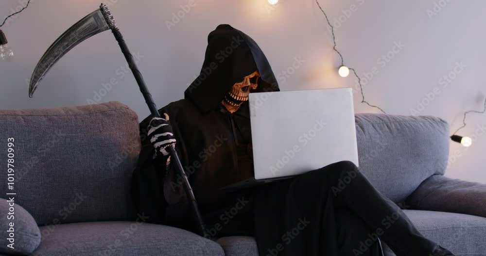 Grim reaper sitting on sofa in living room, using laptop computer ...