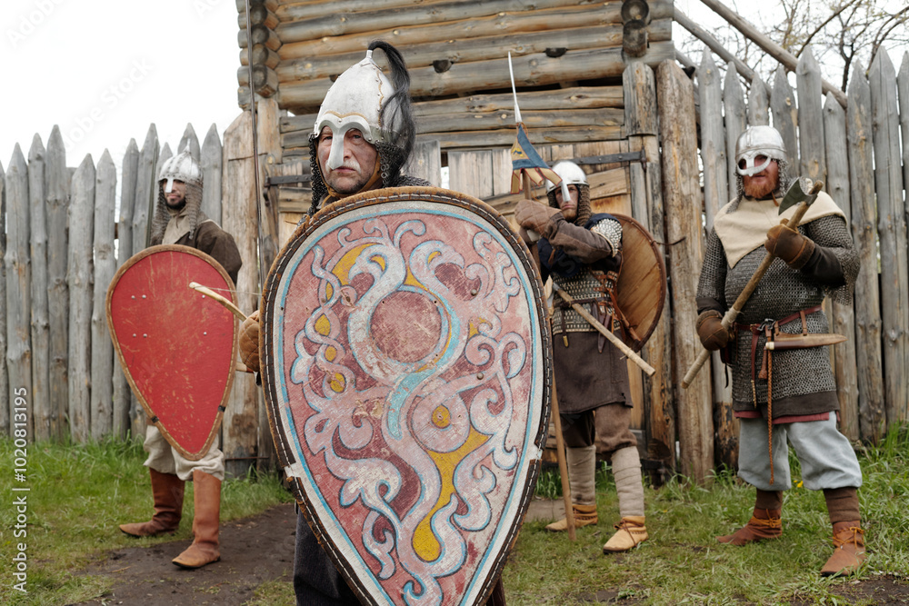 Four Viking reenactors holding shields and weapons, donning traditional ...