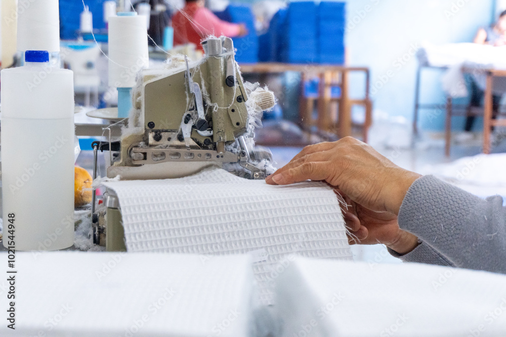 Manos expertas cosiendo tela blanca en una máquina overlock, Detalle de ...