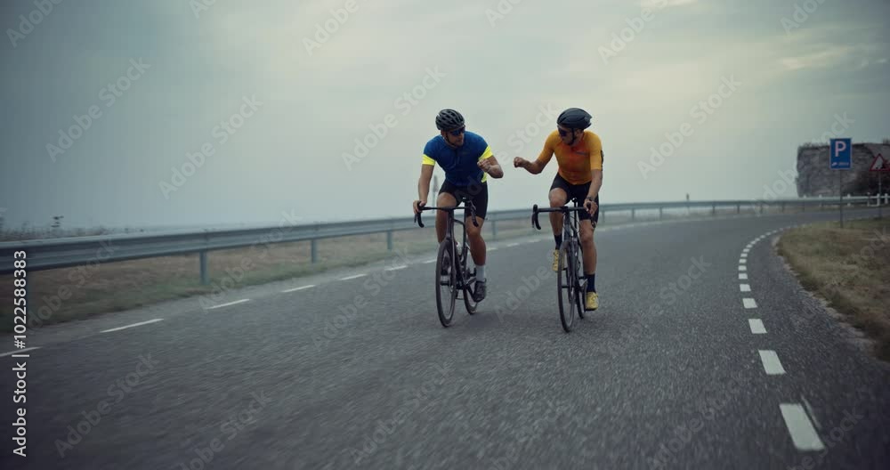 Two Professional Cyclists Ride Side by Side on a Scenic Road, Sharing a ...