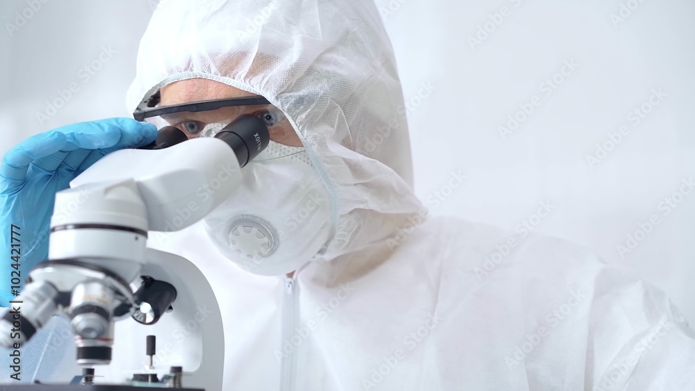 Scientist in ppe analyzing samples using a microscope in a laboratory setting. Close-up of a ...