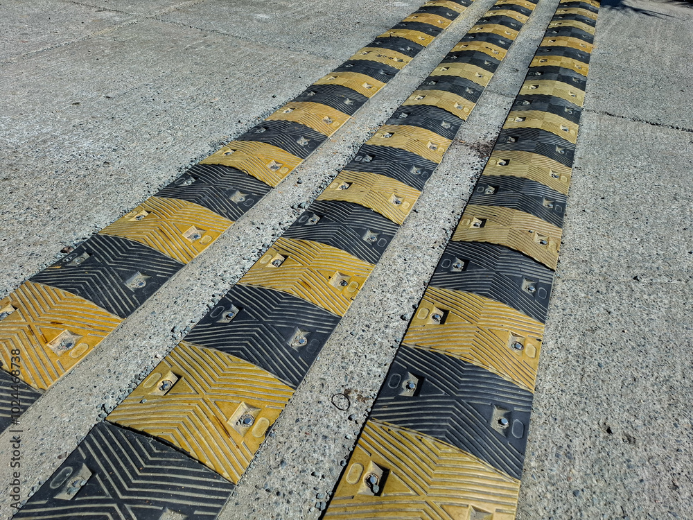 The three yellow and black speed bumps function to force the vehicle to ...