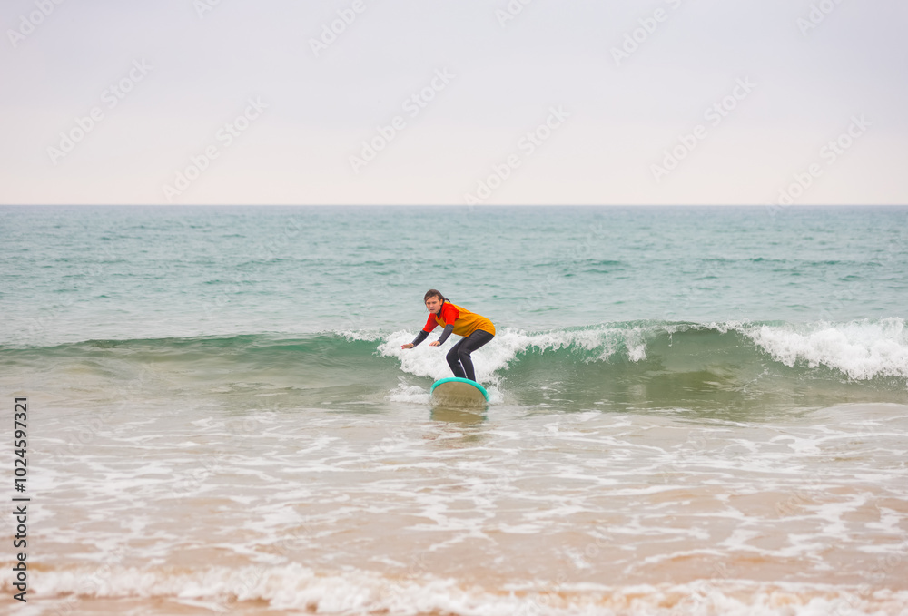 Surfer. Teenage girl learning to surf on foam in the ocean. First ...