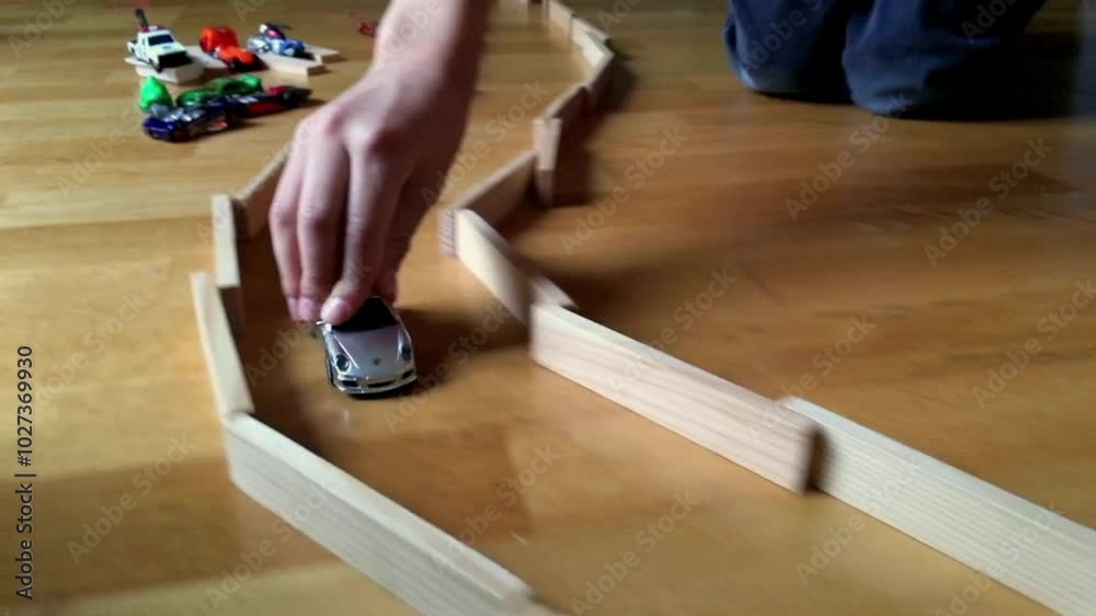 Hands pushing toy car along a wooden block pathway, creating a fun and ...