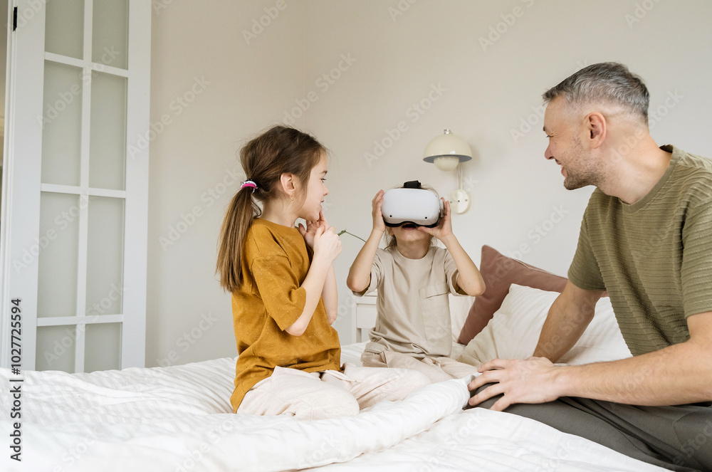 A father is watching his two daughters as they play with a VR headset ...